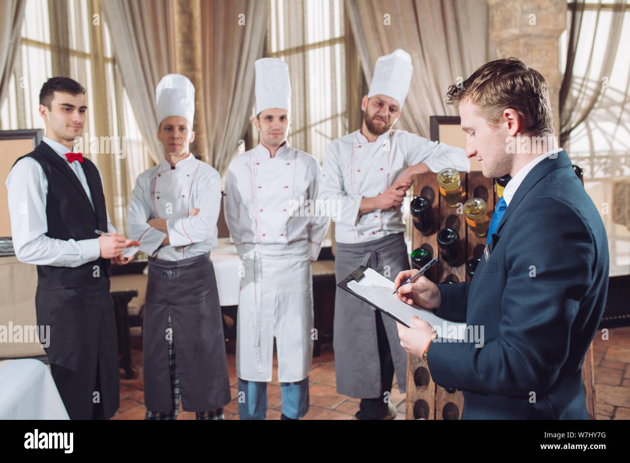 restaurant manager and his staff in kitchen. interacting to head chef ...
