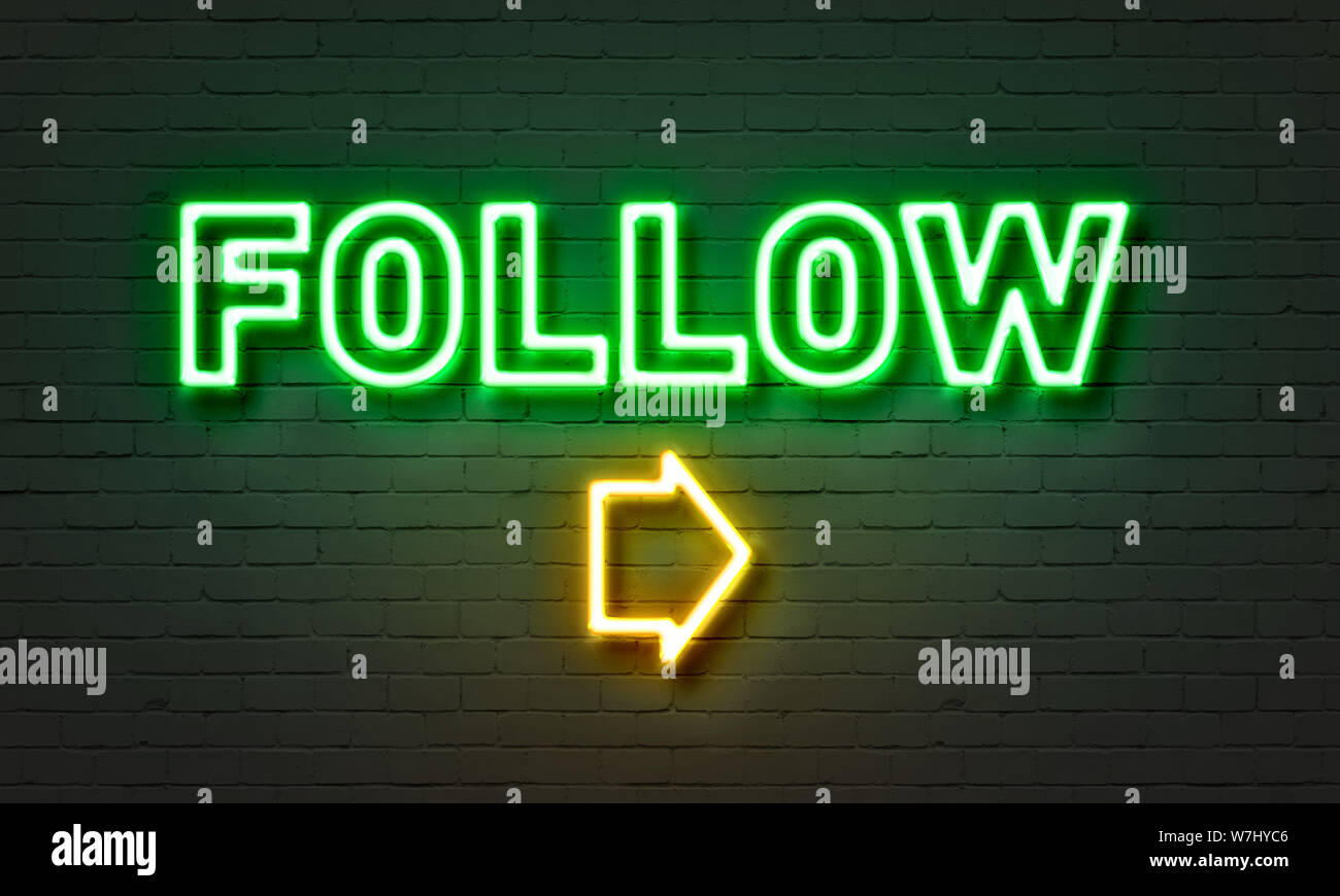 Follow neon sign on brick wall background Stock Photo - Alamy