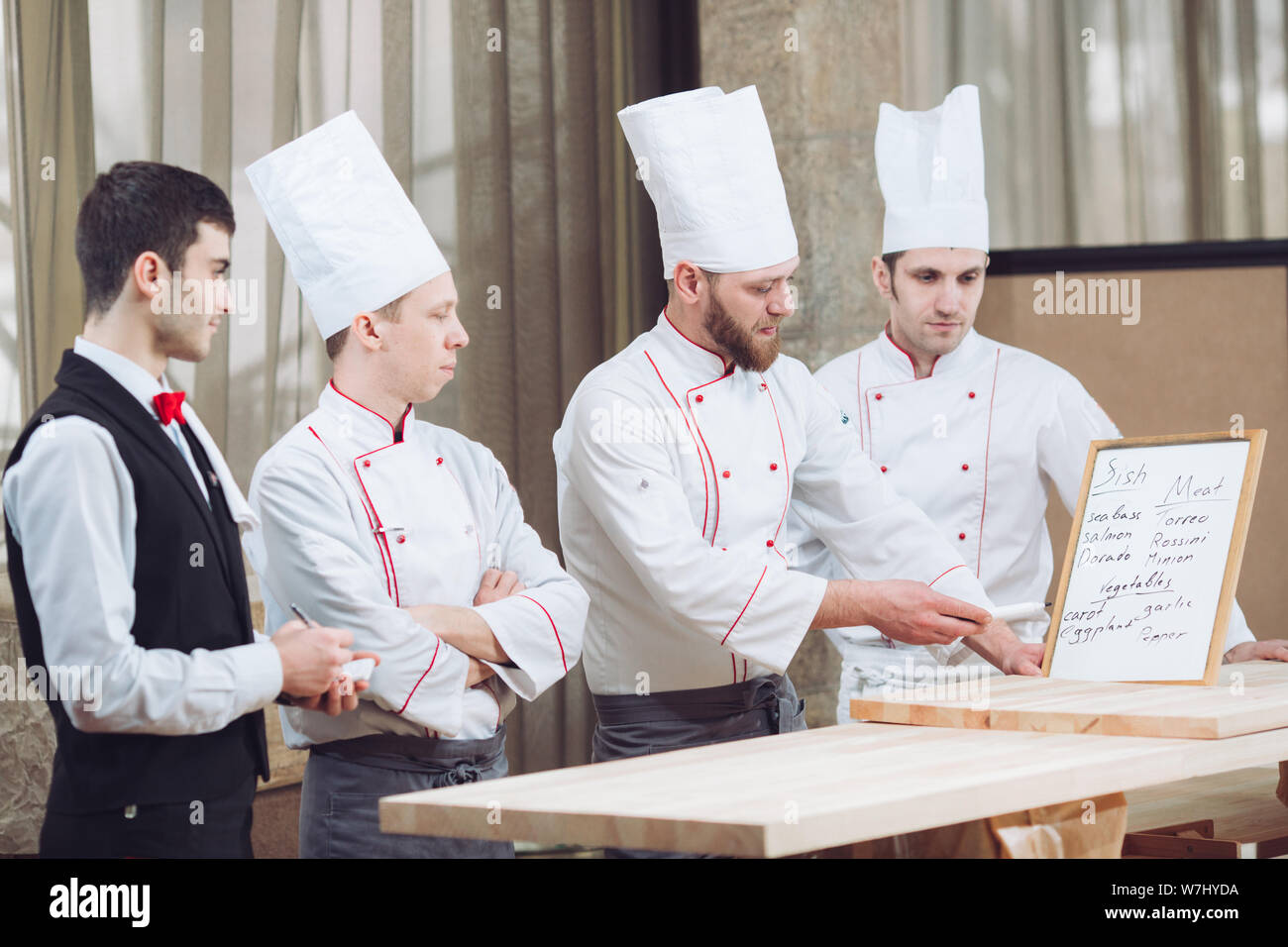 Head Chef and his staff in kitchen. interacting to in commercial ...