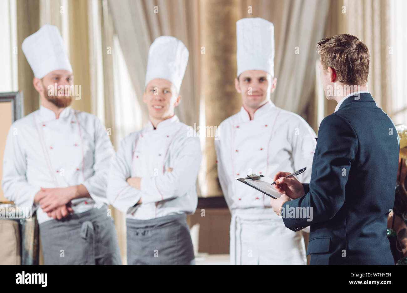 restaurant manager and his staff in kitchen. interacting to head chef ...