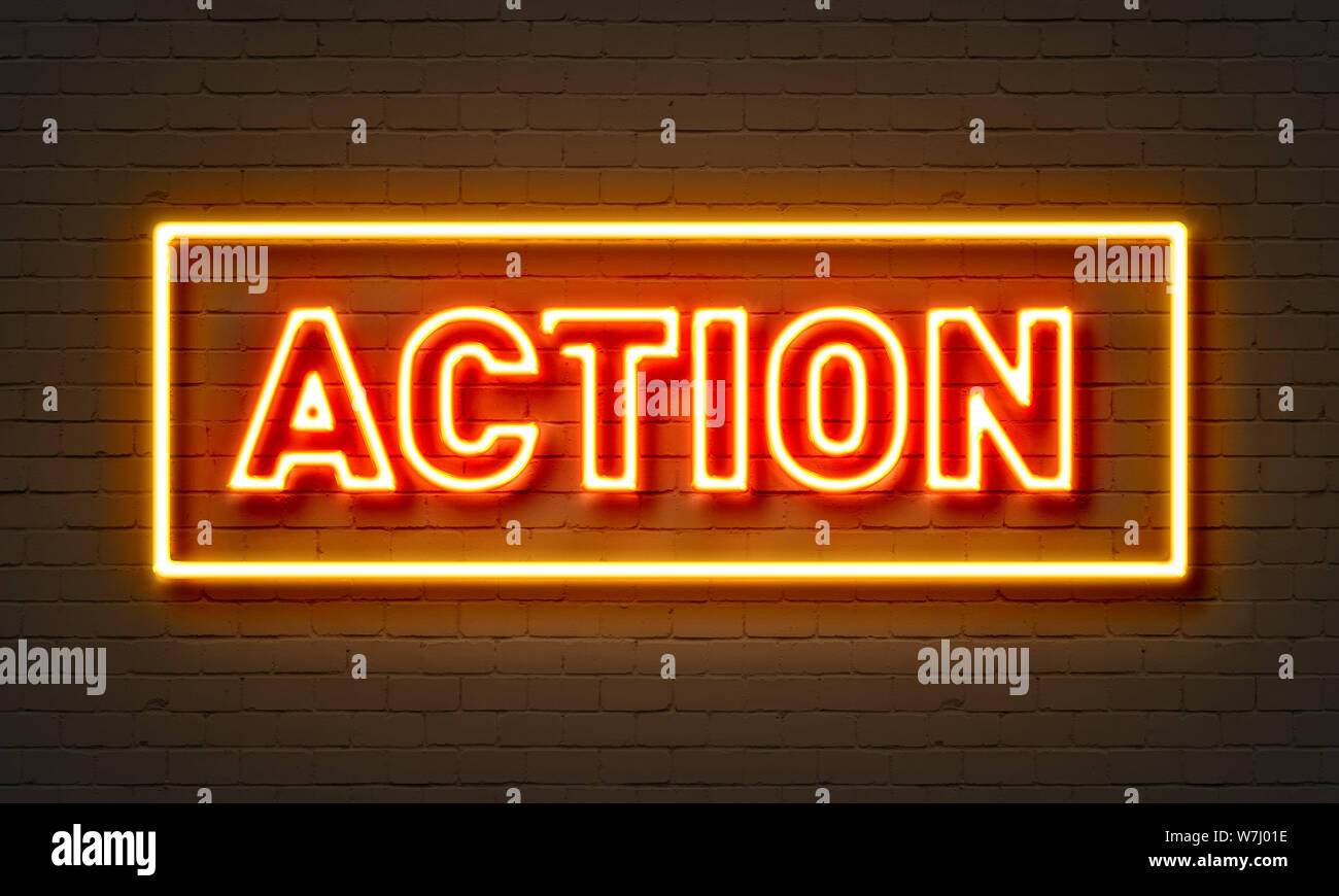 Action neon sign on brick wall background Stock Photo - Alamy