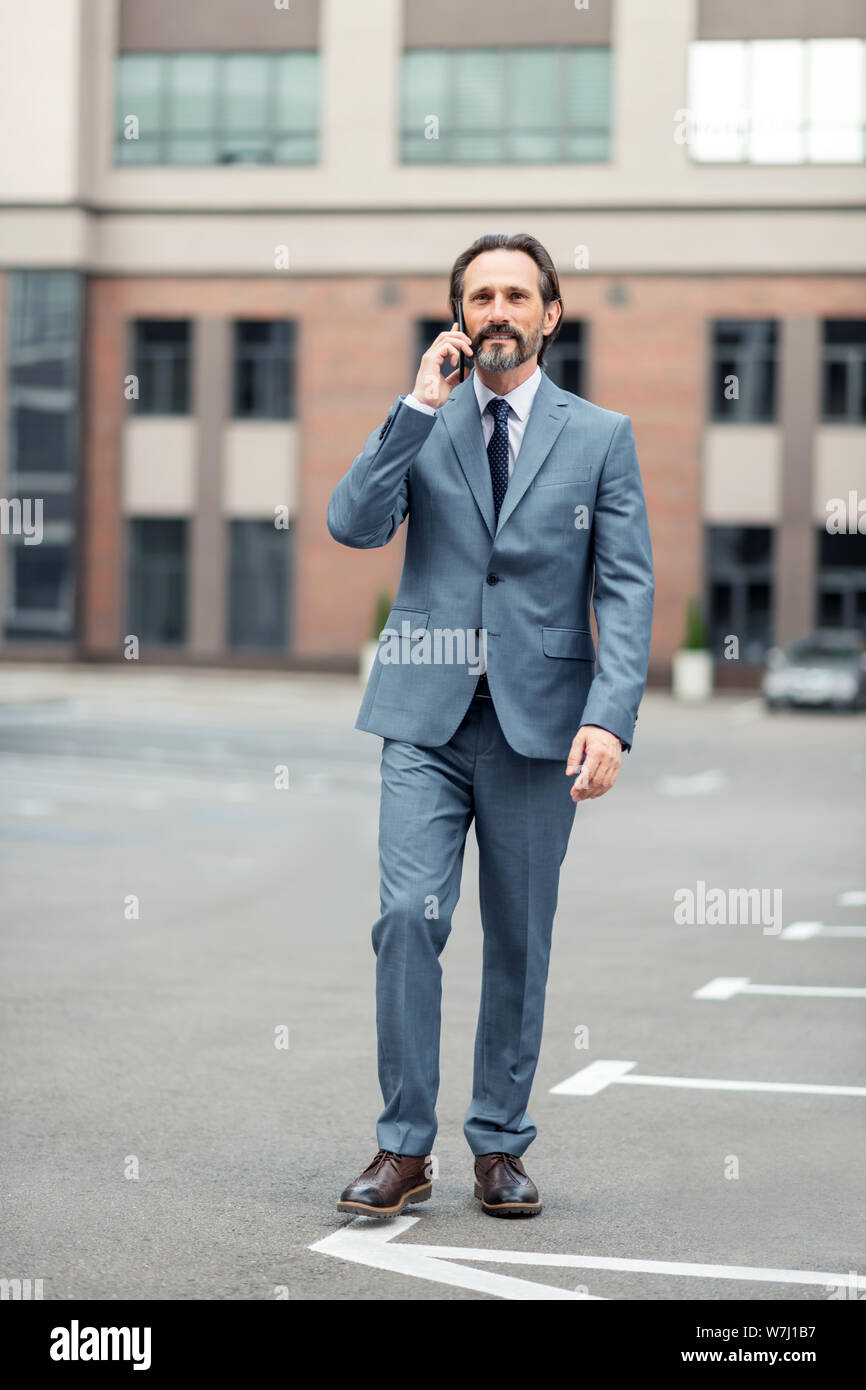 Man wearing grey suit calling colleague while walking by foot Stock ...