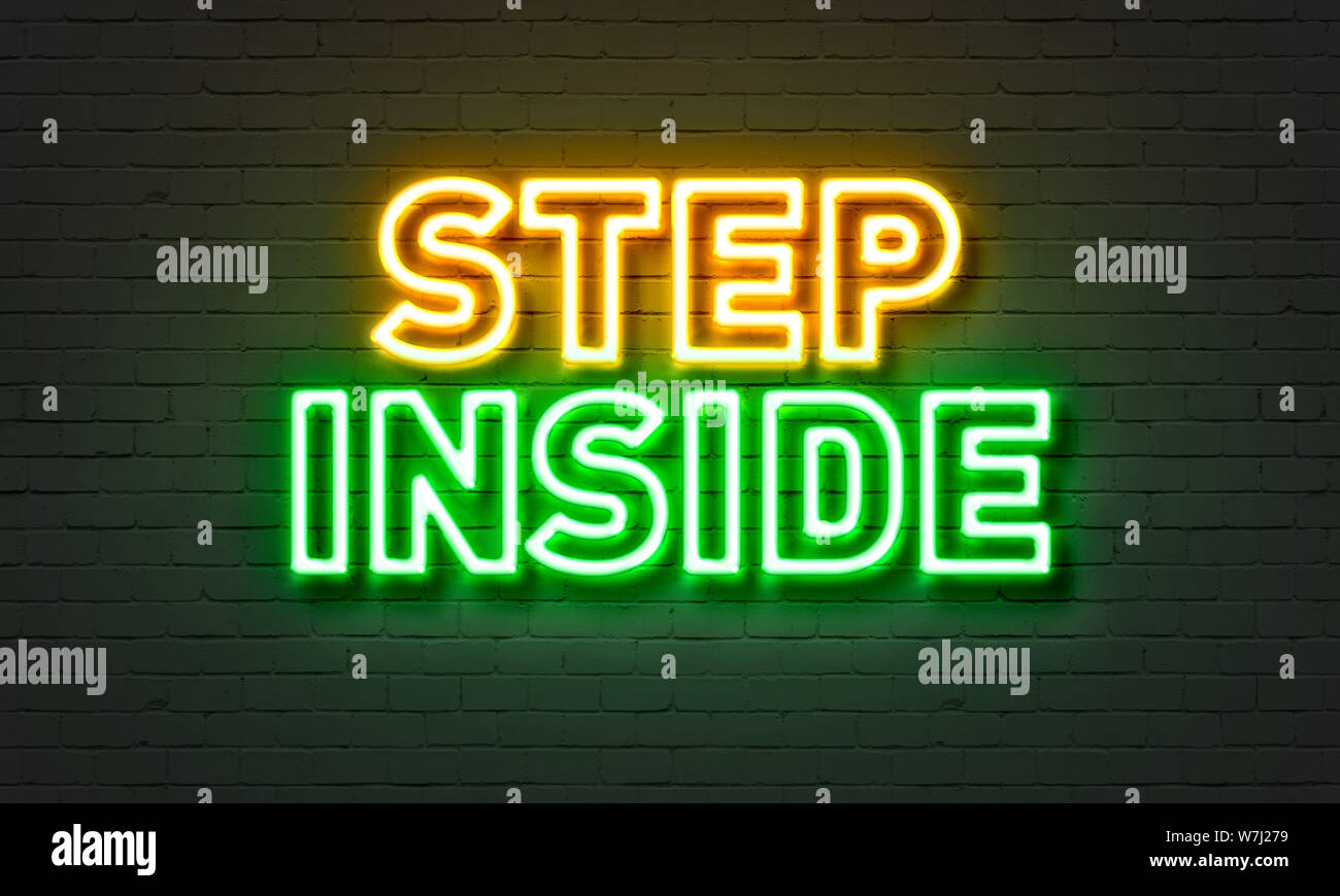 Step inside neon sign on brick wall background Stock Photo - Alamy