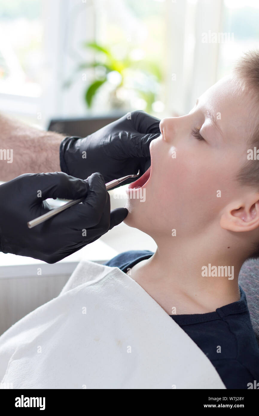 Tooth inspection of a child by a dentist. The boy is sitting on a ...