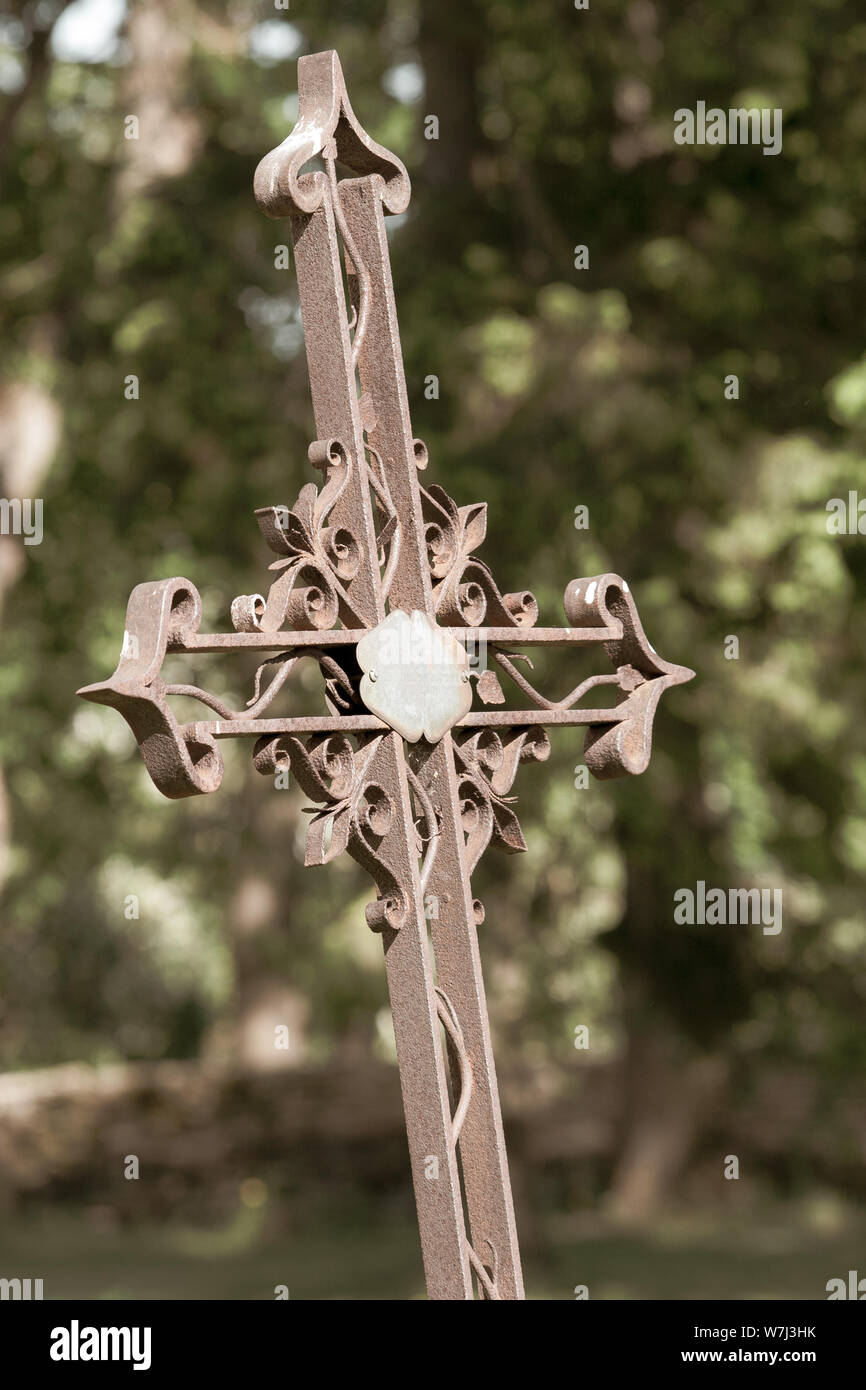 Inclined old curly iron forged cross. Green background with blurred ...