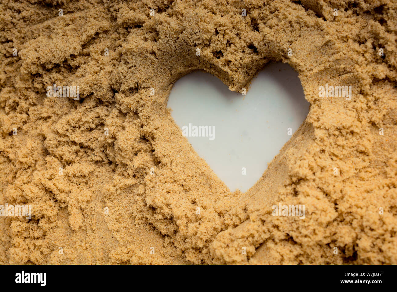 Heart shape made on the sand background in view Stock Photo - Alamy