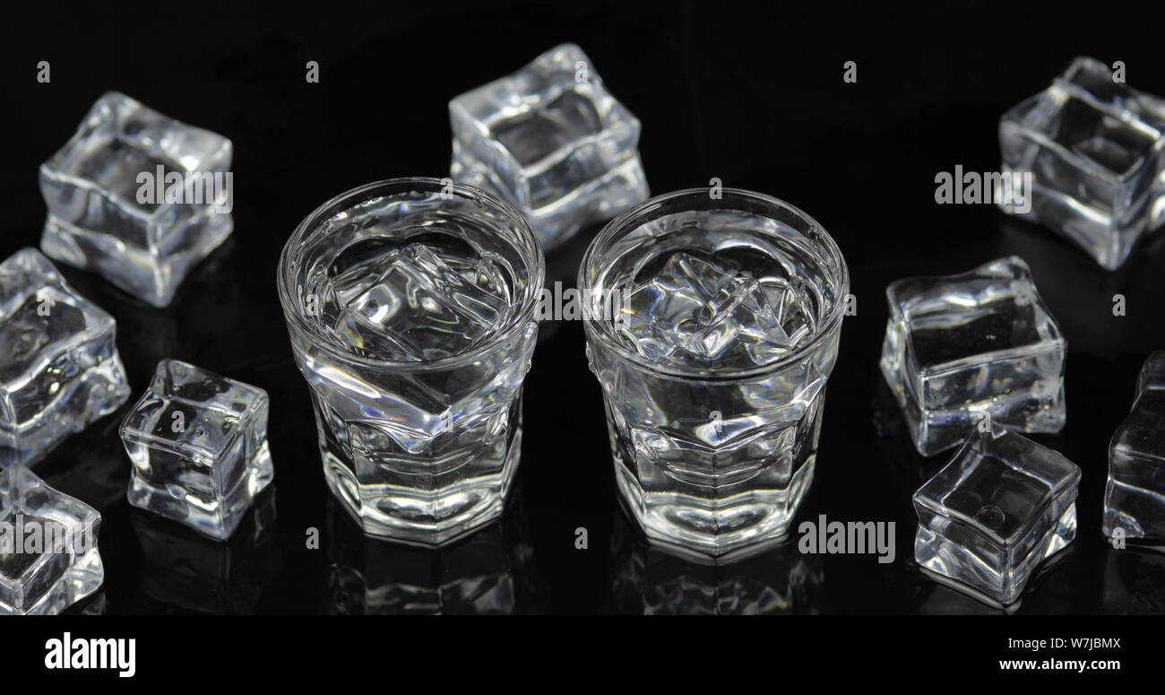 Shots of vodka with ice cubes against black background. Alcohol drink ...