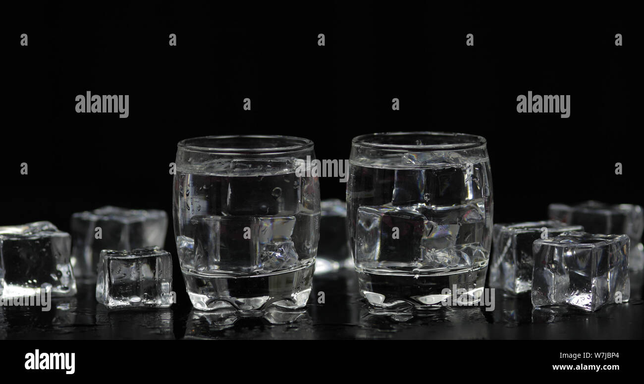 Shots of vodka with ice cubes against black background. Alcohol drink ...