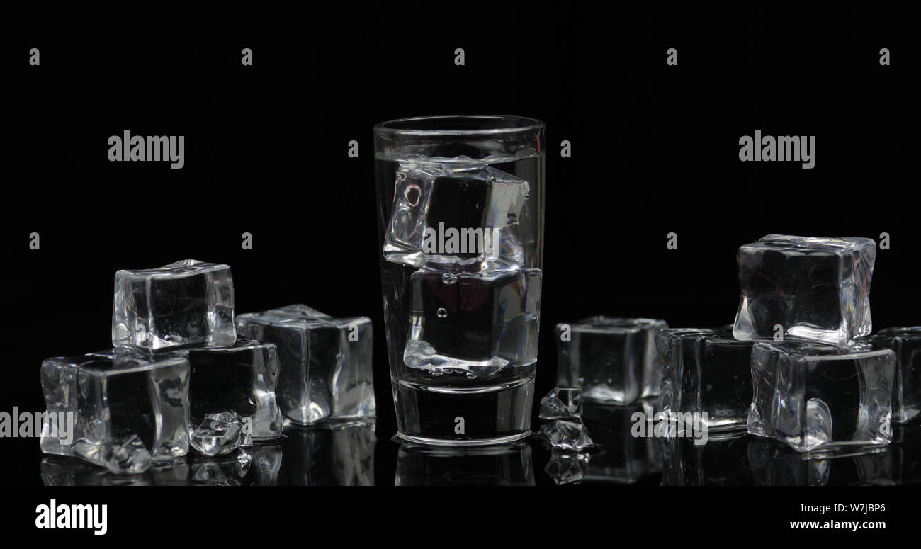 Shot of vodka with ice cubes against black background. Alcohol drink ...