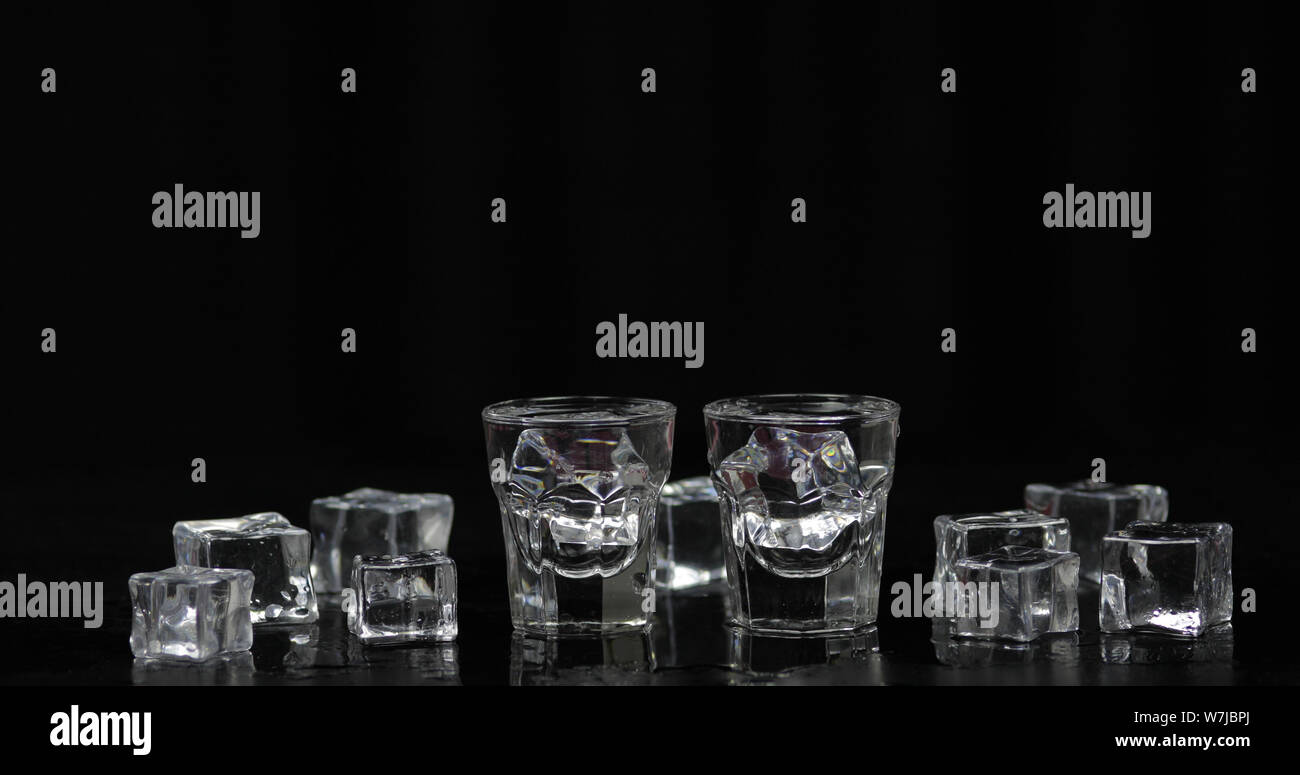 Shots of vodka with ice cubes against black background. Alcohol drink ...