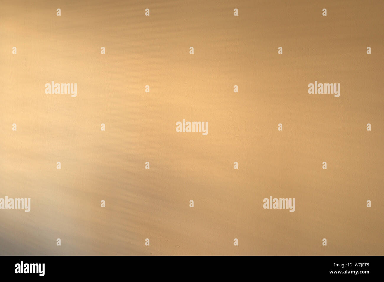 An empty wall with a light gradient created by shadows streaking across ...