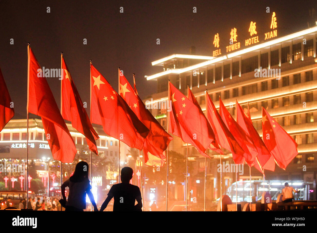 Chinese national flags flutter at night outside the Xi'an Bell Tower ...