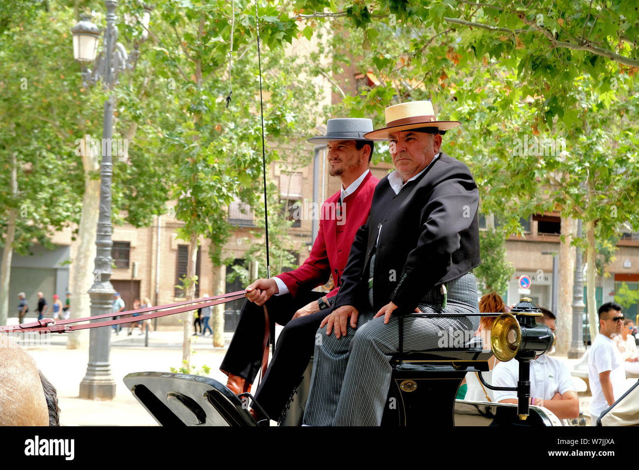 Two men in traditional Spanish costume atop a horse drawn carriage ...
