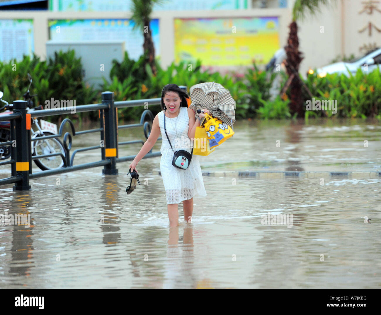 A pedestrian walks on a flooded road in strong wind and heavy rain ...