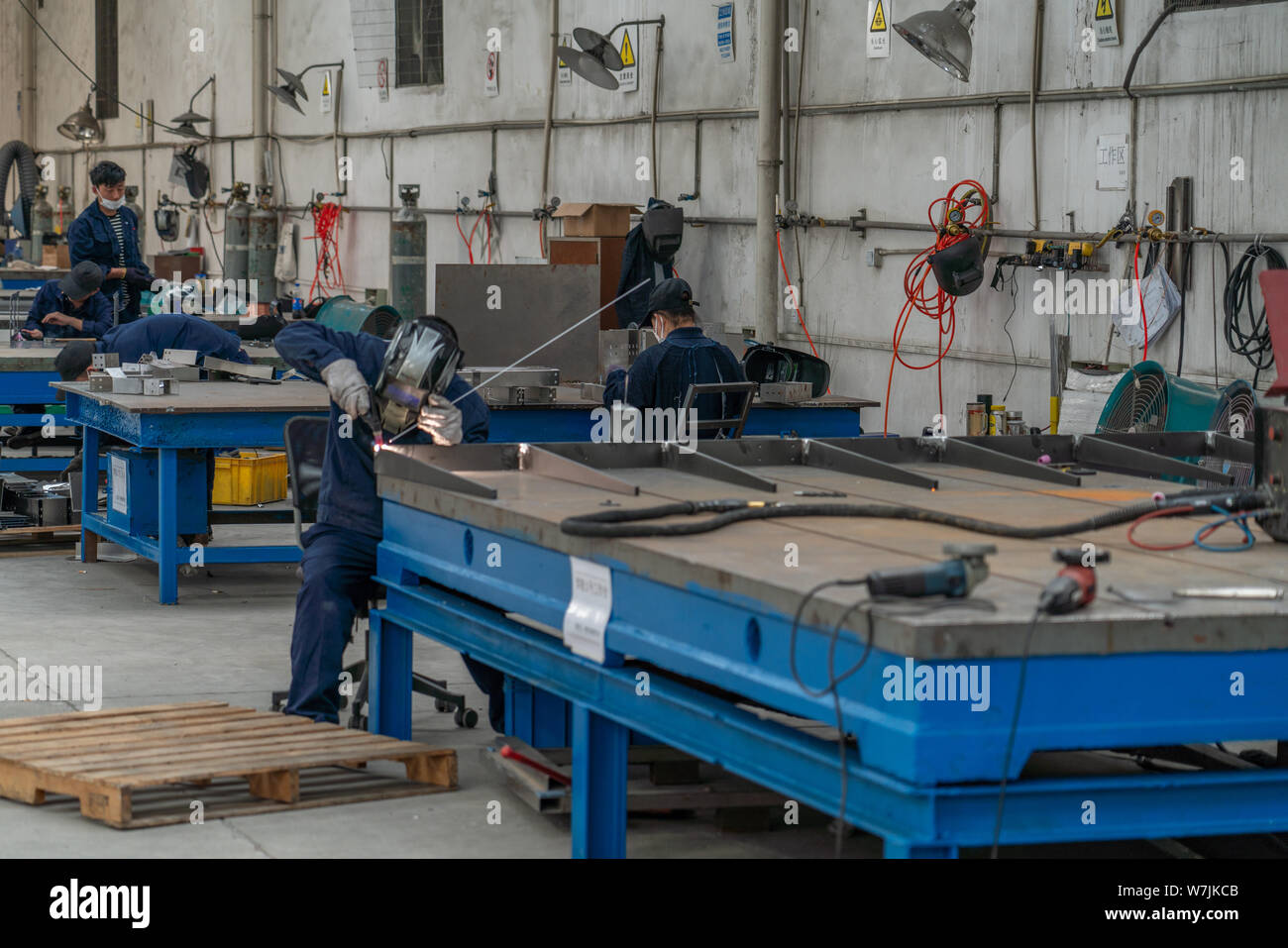 Chinese factory work welds stainless steel parts at a factory near ...