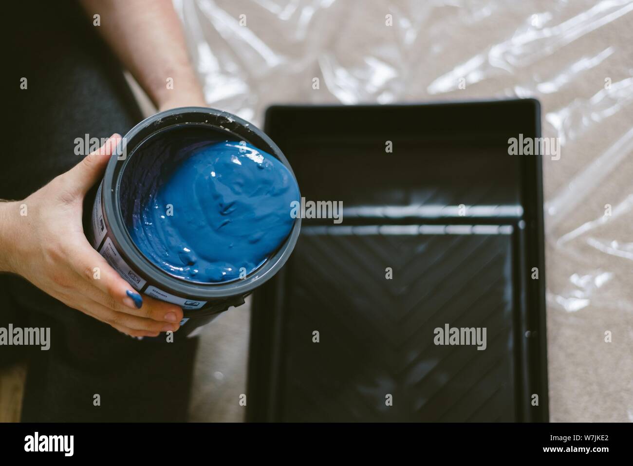 Person holding a bucket of blue wall paint Stock Photo - Alamy