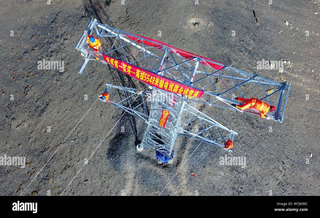 Electricity workers labour on the world's highest power transmission tower with a height of ...