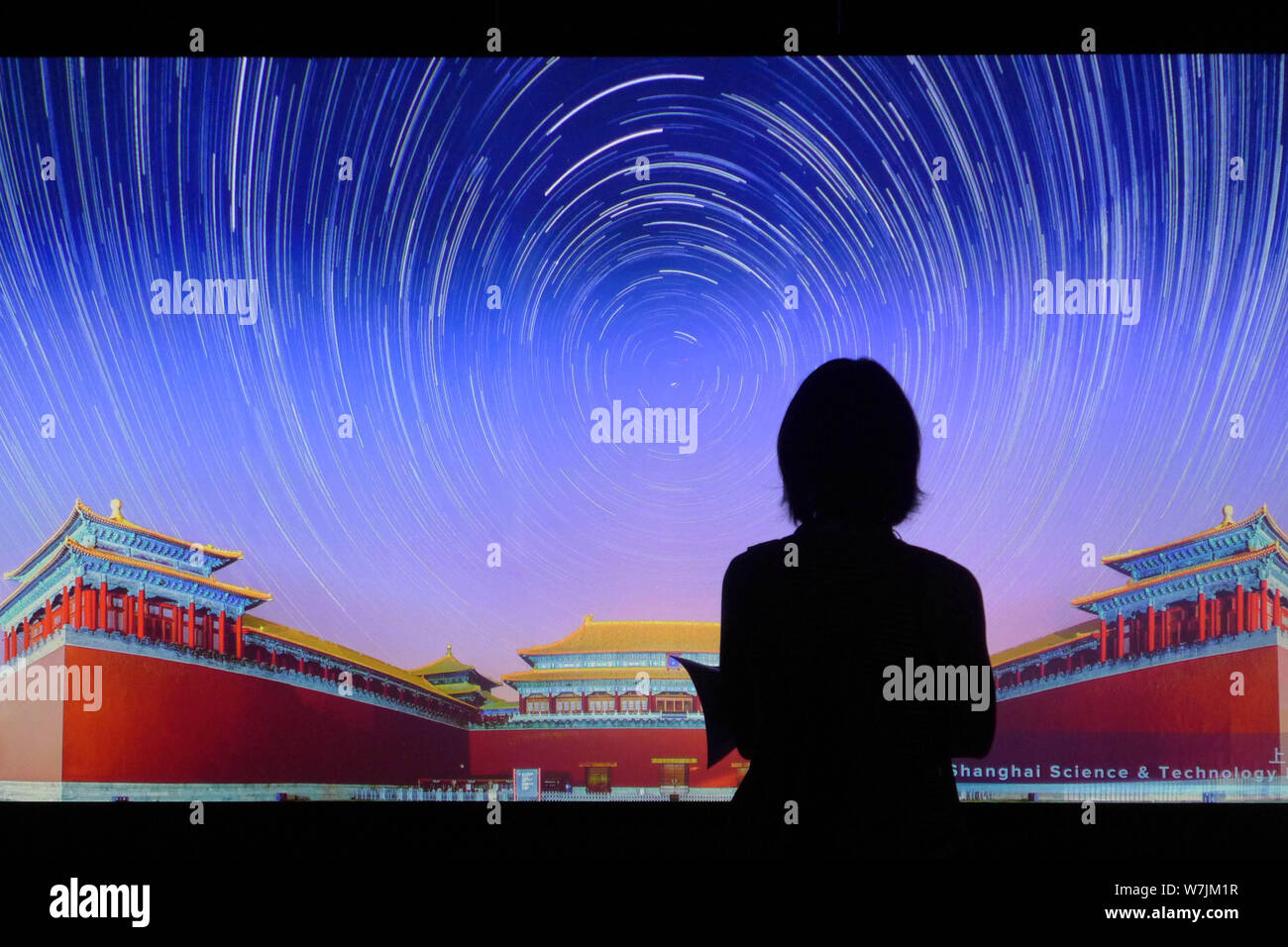 A visitor looks at the starry sky over Beijing's Forbidden City in a ...