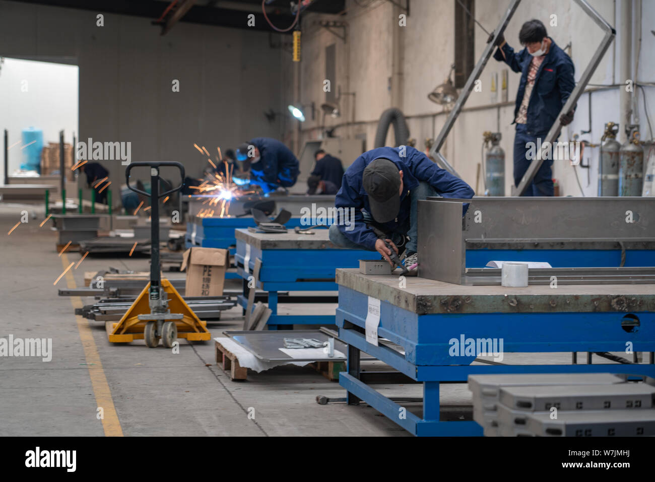 Chinese factory workers assembly and weld parts in a metal ...