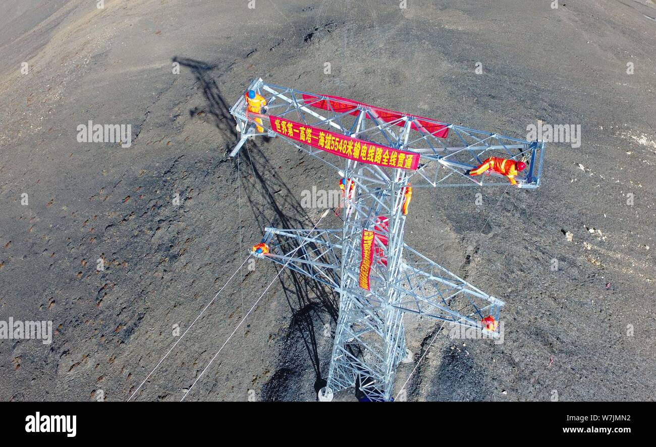 Electricity workers labour on the world's highest power transmission tower with a height of ...
