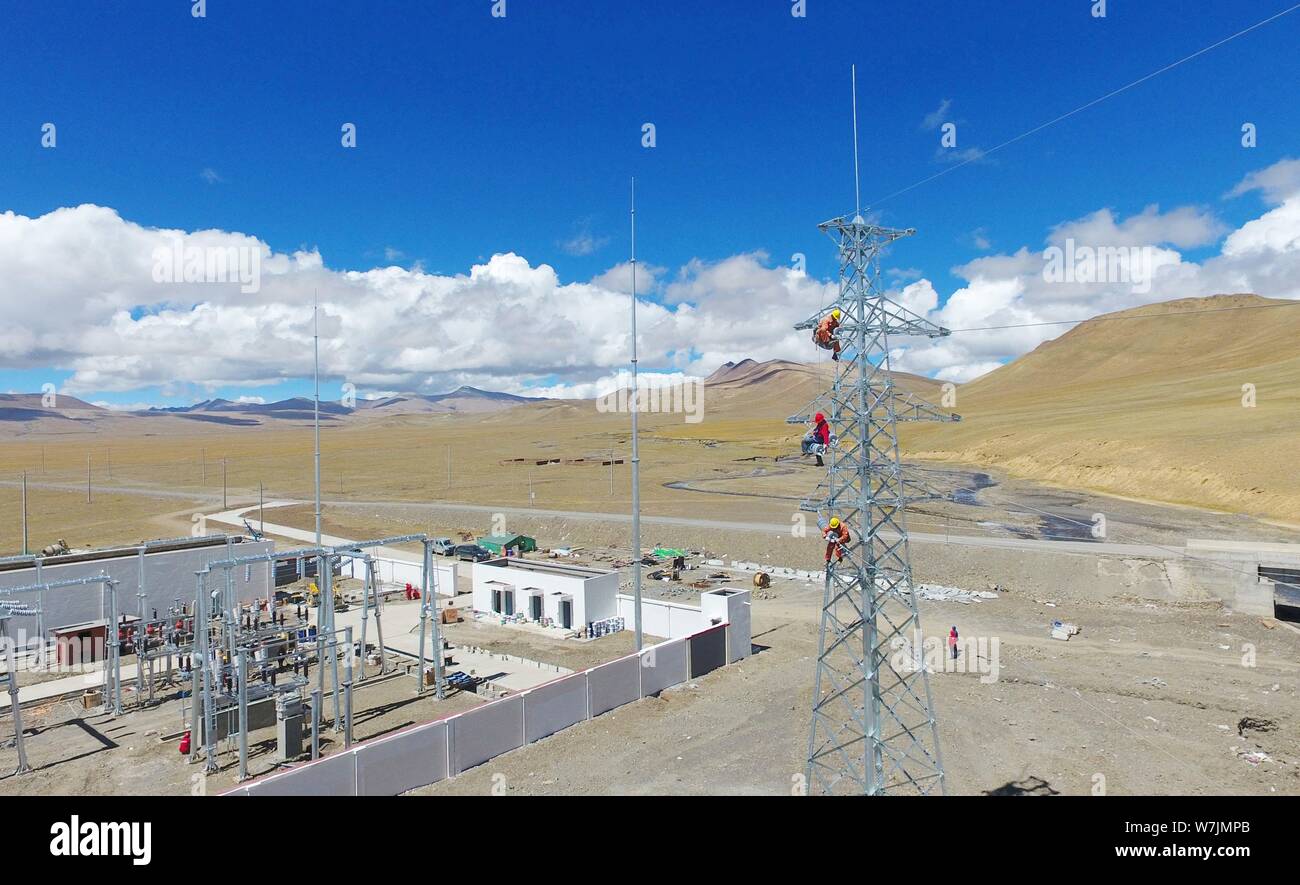 Chinese workers labor at the world's highest power transmission tower lines with a height of ...