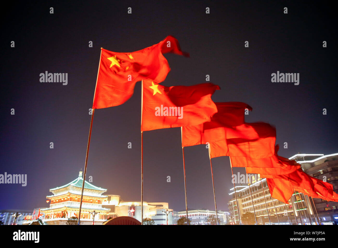 Chinese national flags flutter at night outside the Xi'an Bell Tower ...