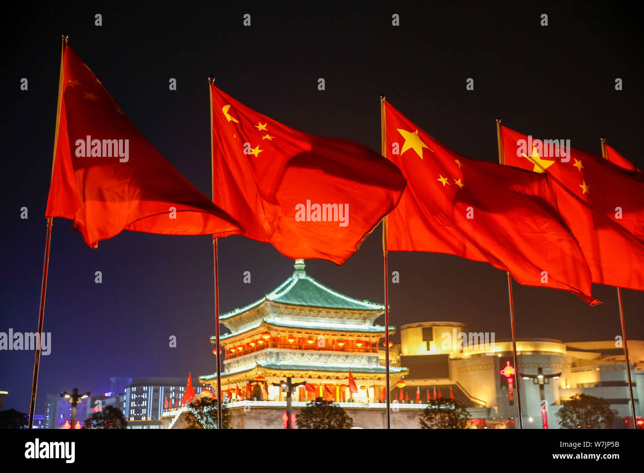 Chinese national flags flutter at night outside the Xi'an Bell Tower ...