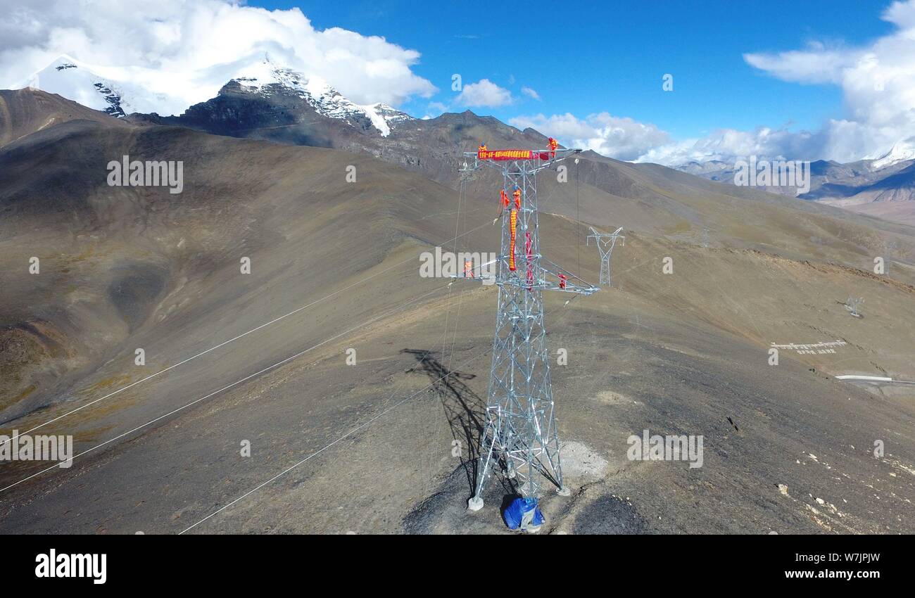 Electricity workers labour on the world's highest power transmission tower with a height of ...