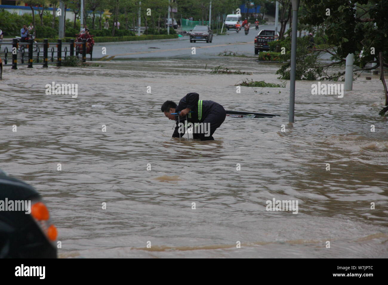 A Chinese worker clears away mud and leaves on a flooded road after ...