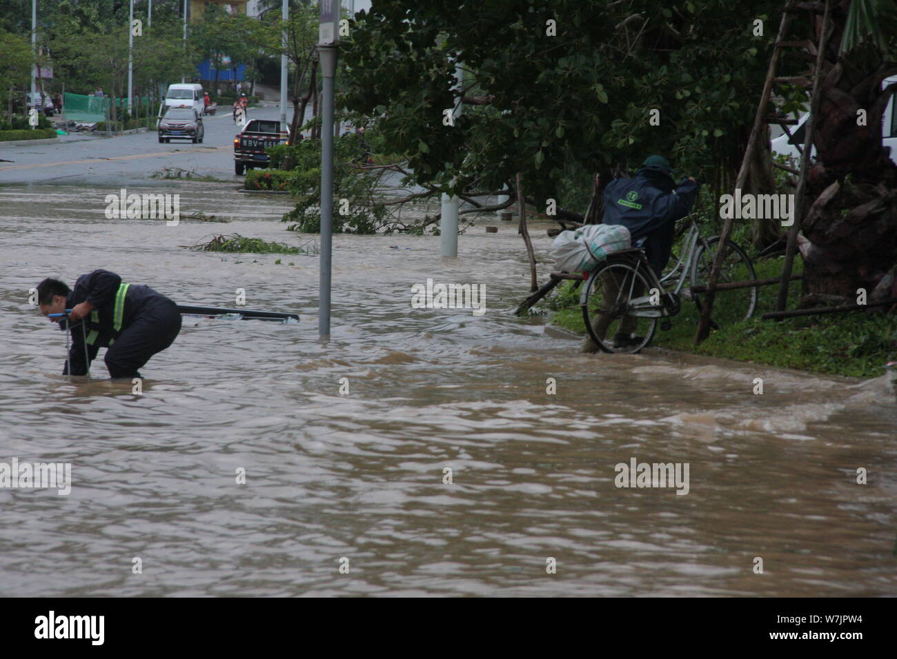 A Chinese worker clears away mud and leaves on a flooded road after ...