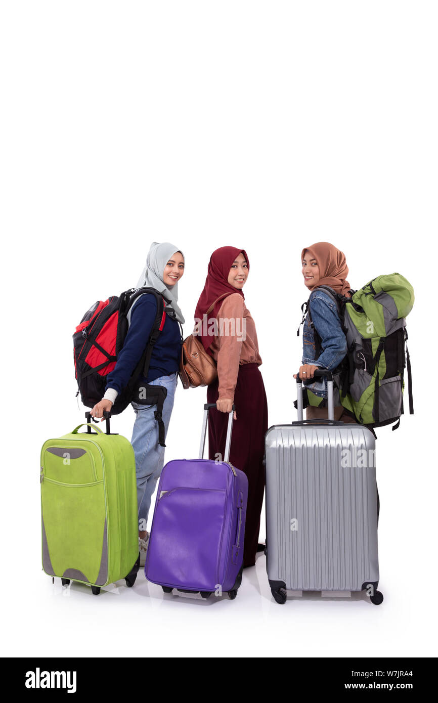 Back view, three hijab woman standing holding suitcase and carrying bag ...