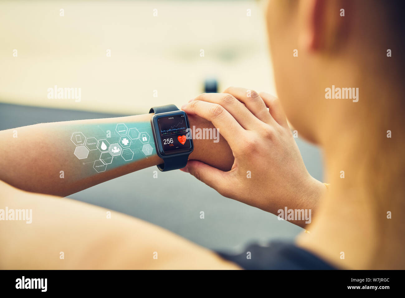 Young woman checking the sports watch with screen healthcare icon ...