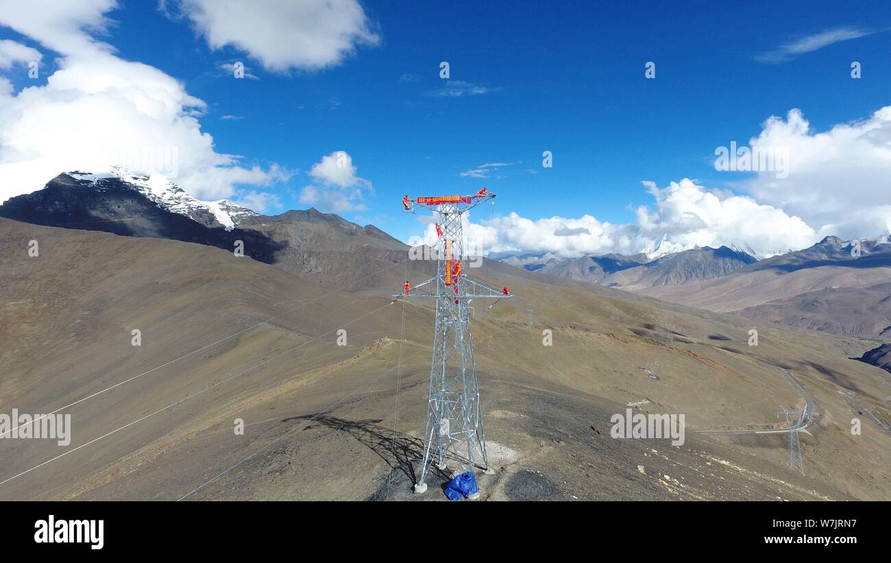 Electricity workers labour on the world's highest power transmission tower with a height of ...
