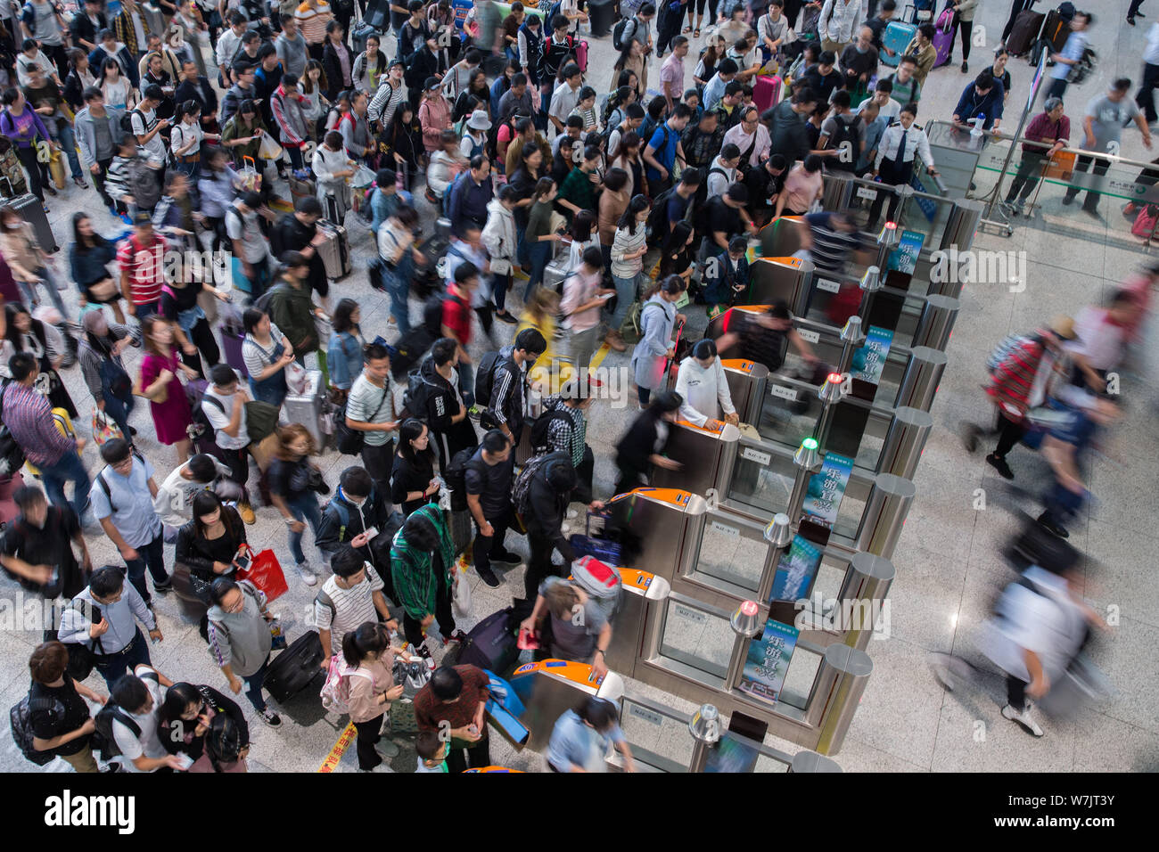 Chinese passengers queue up to check-in at the Nanjing West Railway ...
