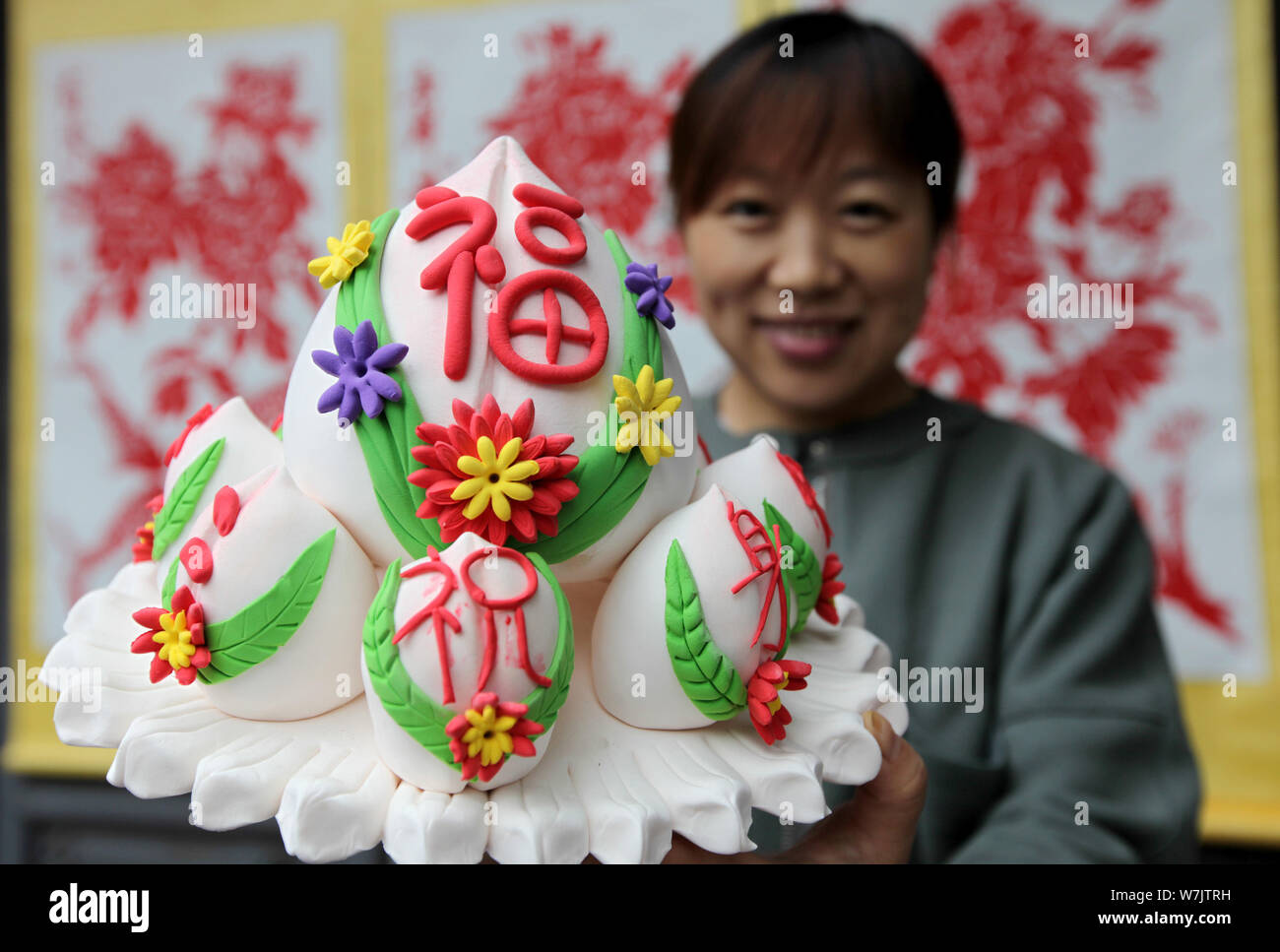 A Chinese folk artist shows flowery buns made by herself with a Chinese ...