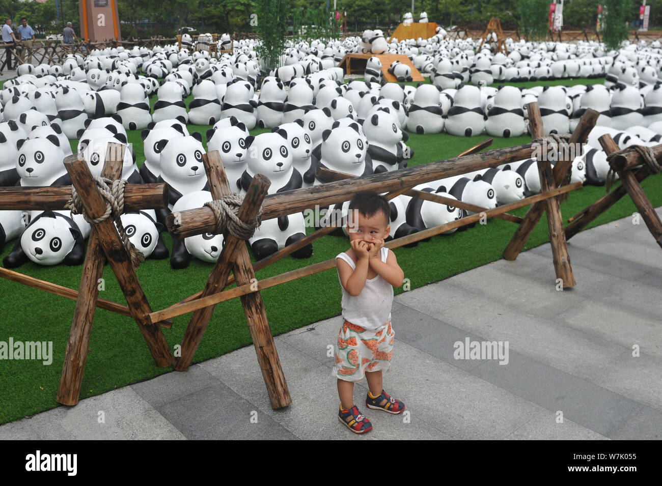 A child poses for photos with giant panda sculptures on display in ...