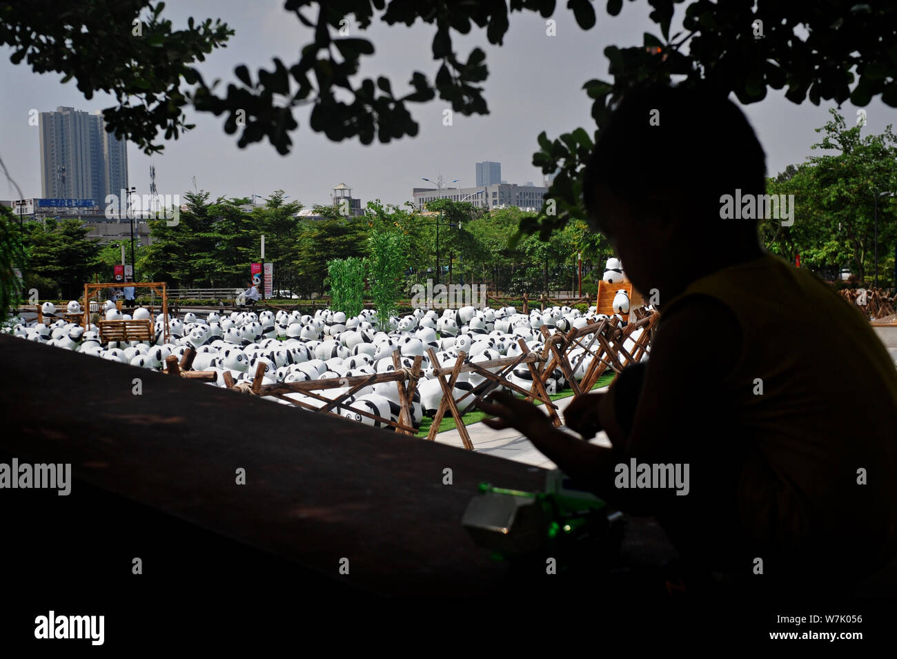 A local resident looks at giant panda sculptures on display in front of ...