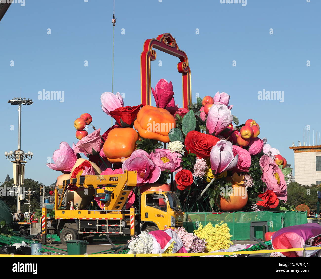 Chinese workers install giant artificial flowers and fruits to set up a ...