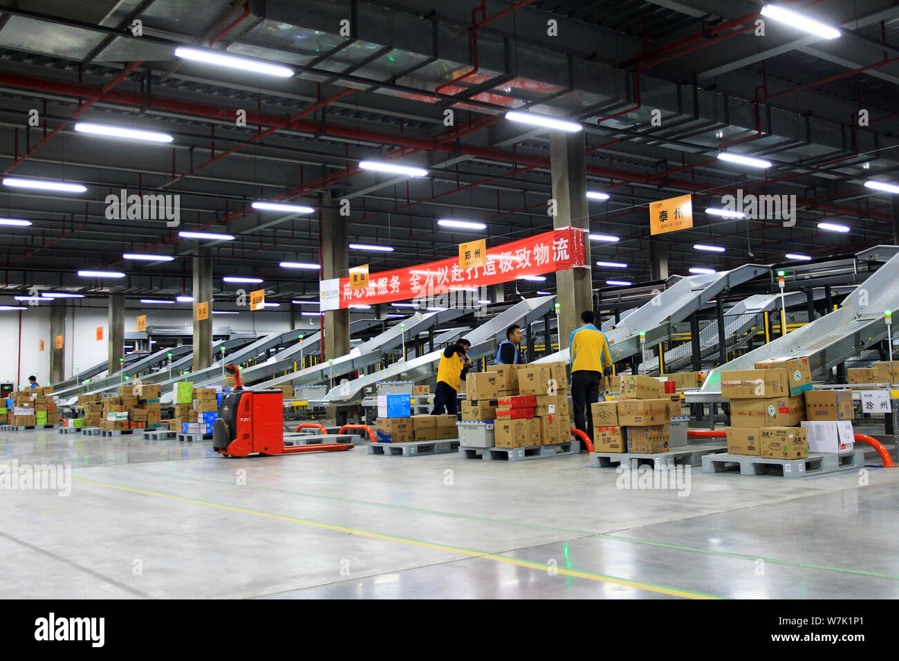 Chinese workers sort piles of parcels at the smart warehouse in the ...