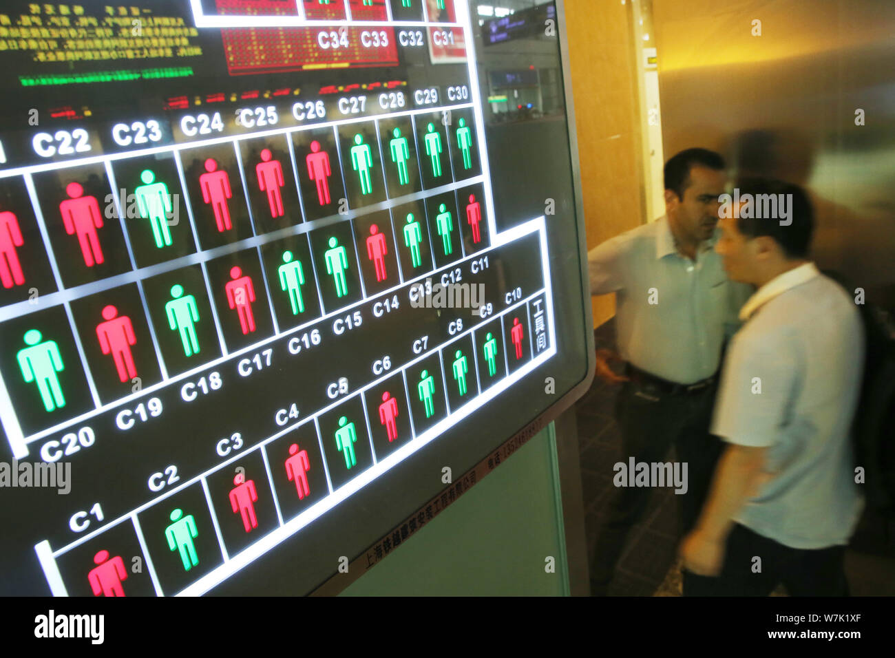 Passengers walk past the electronic screen showing the real-time ...