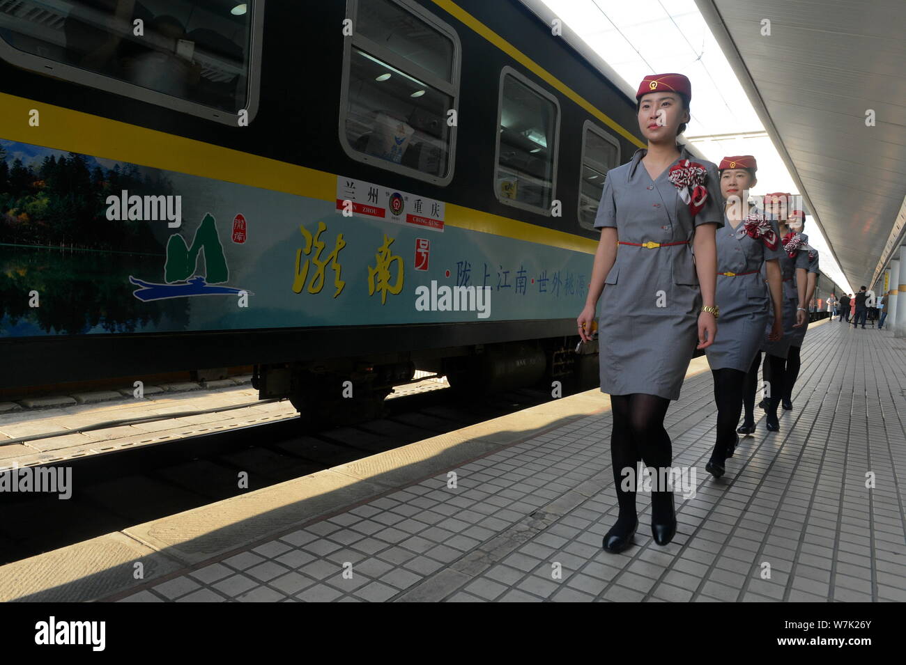 Chinese train attendants walk past a train on the Lanzhou-Chongqing ...