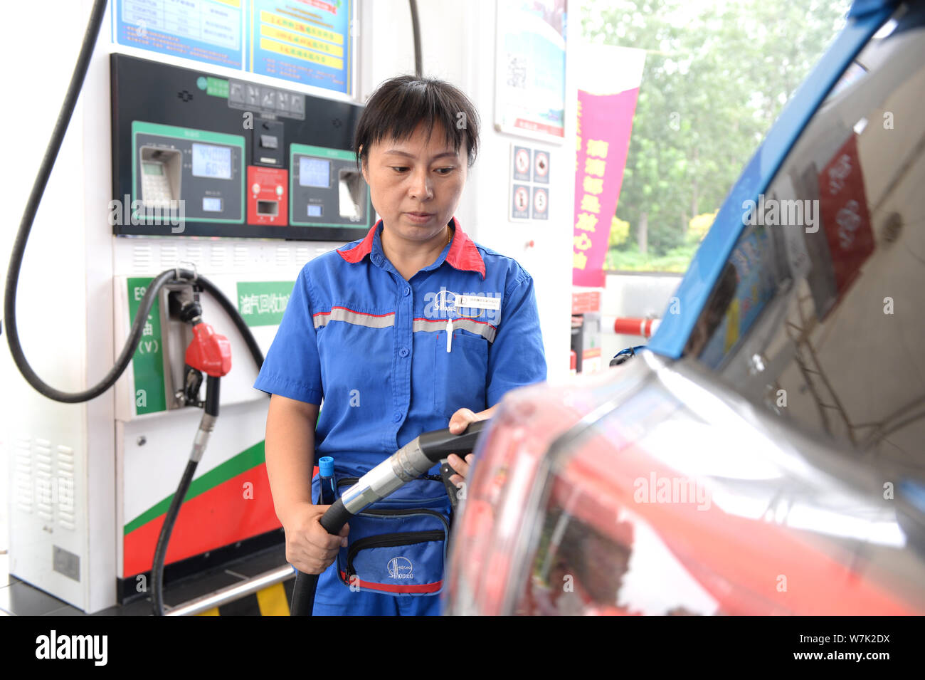 A Chinese worker refuels a car with ethanol gasoline at a gas station ...