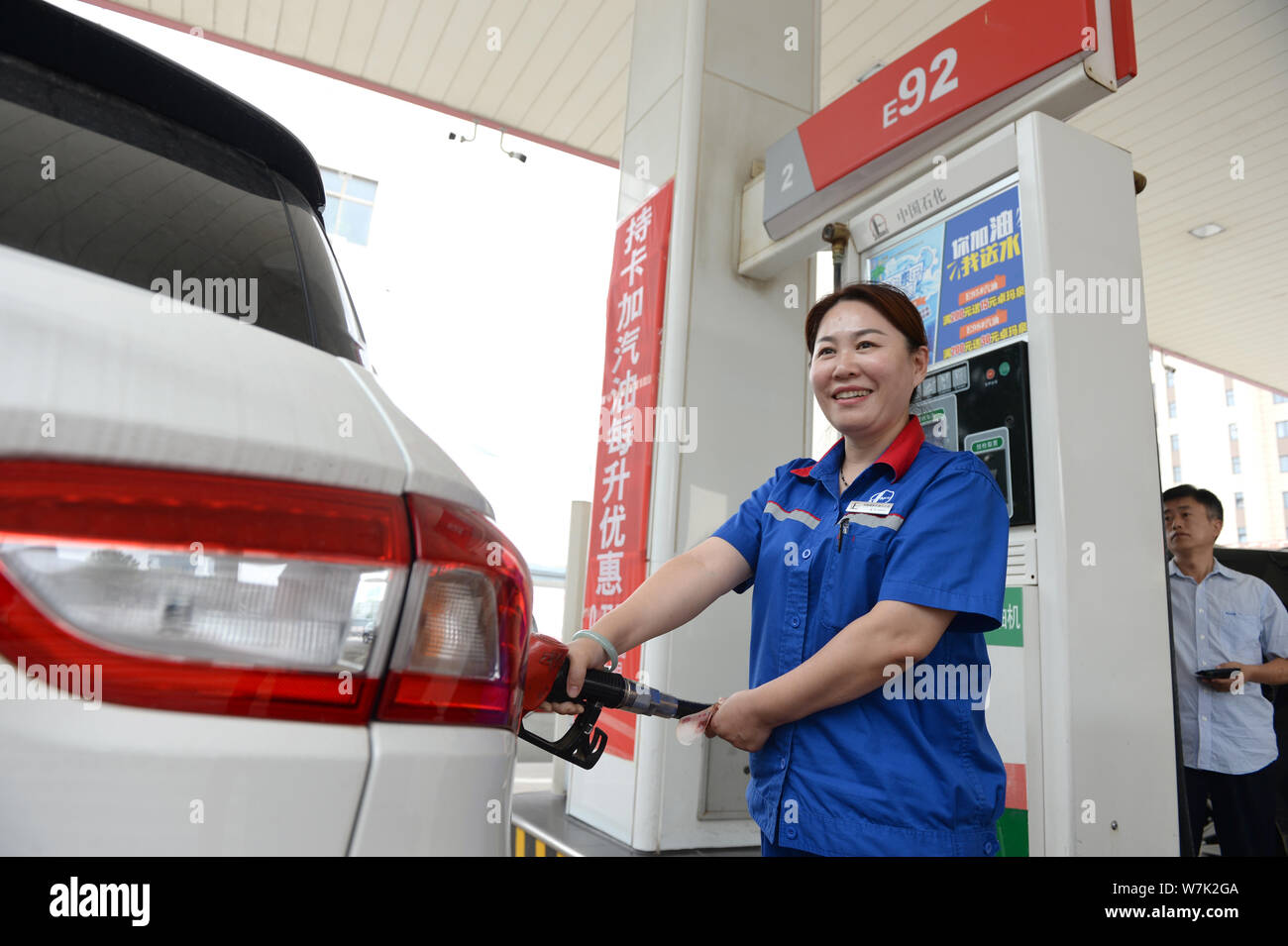 A Chinese worker refuels a car with ethanol gasoline at a gas station ...