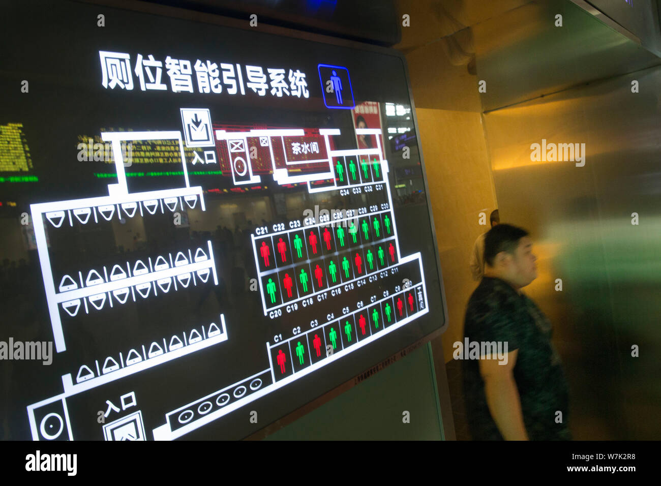 A passenger walks past the electronic screen showing the real-time ...