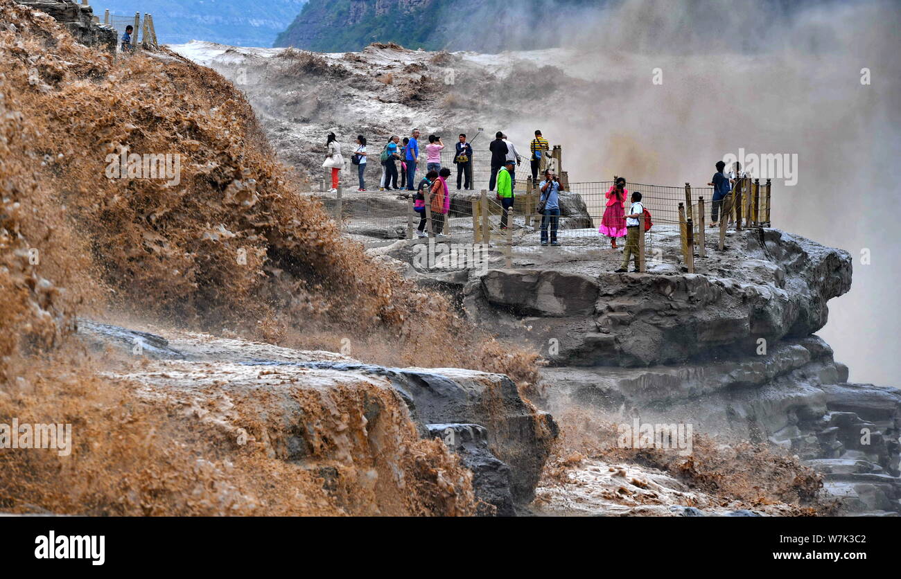 Tourists visit the roaring Hukou Waterfall on the Yellow River due to ...