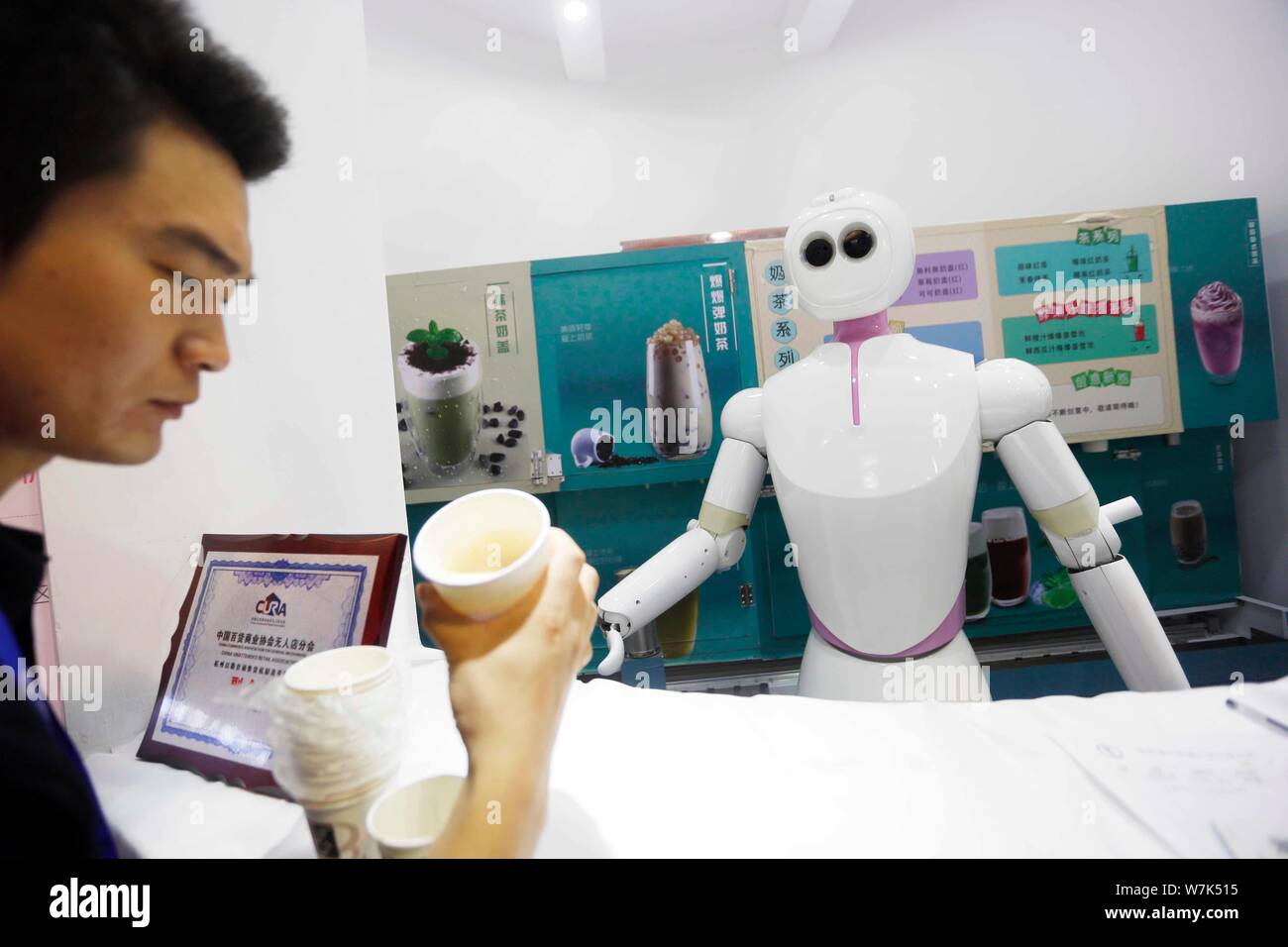 A visitor looks at the tea made by a robot during the Shanghai ...