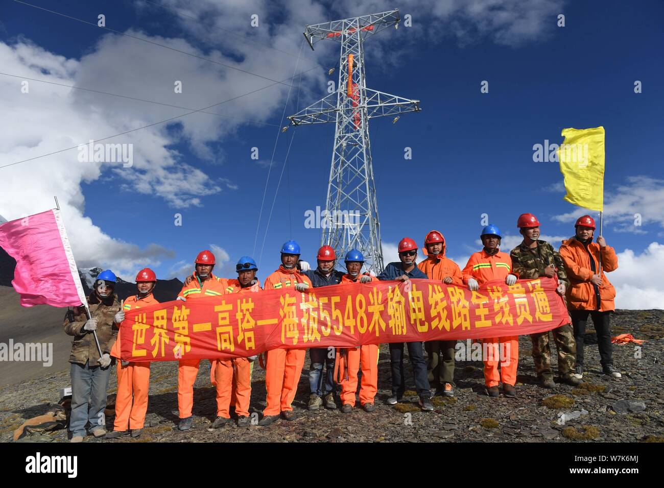 Electricity workers hold a banner to celebrate the completion of the world's highest power ...