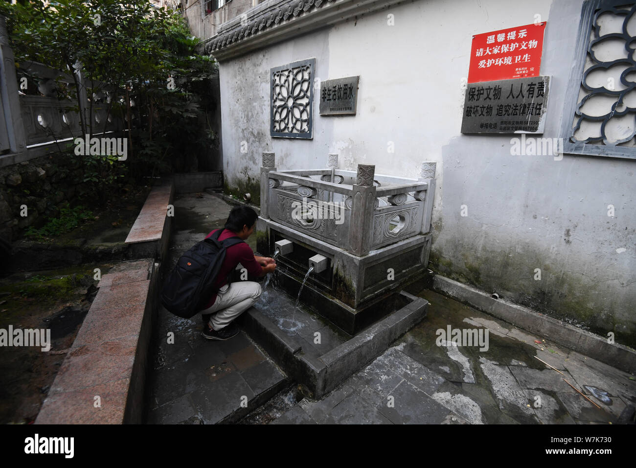A tourist uses the well water from the 600-year-old Yujing Ancient Well ...