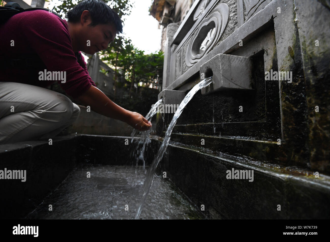 A tourist uses the well water from the 600-year-old Yujing Ancient Well ...