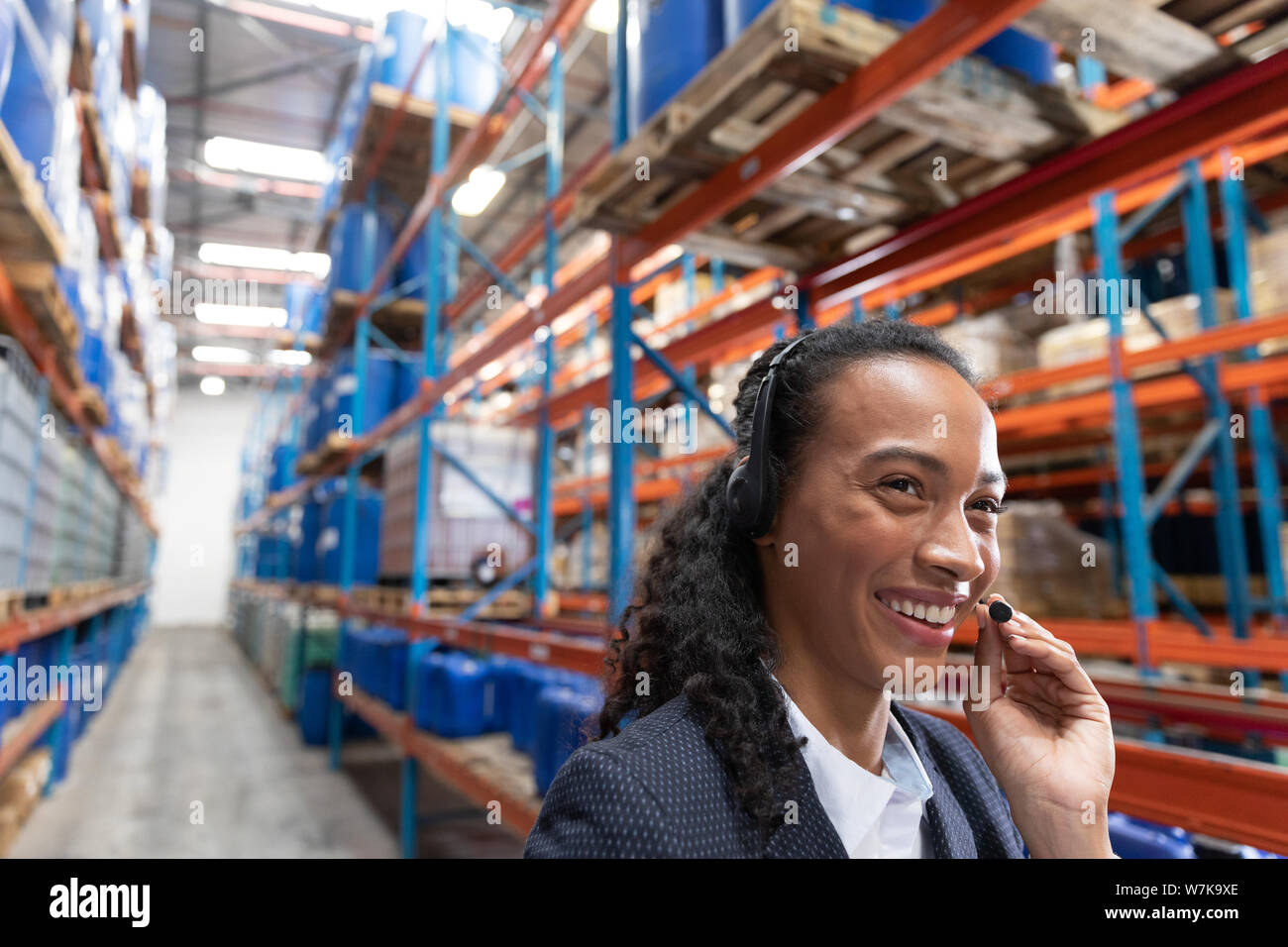 Female manager talking on headset in warehouse Stock Photo - Alamy